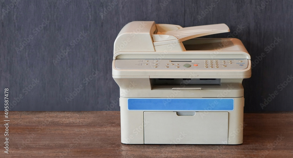 front view white and blue printer on wooden floor, grey wooden wall ...