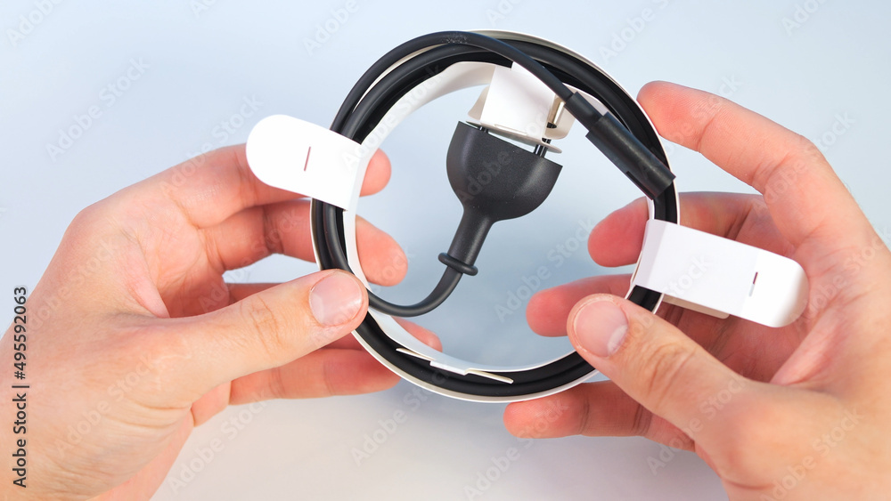 Unpacking a new black power cable on white table , top view. Overhead ...