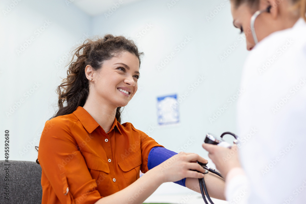 Nurse measuring blood pressure of a woman patient during an examination ...