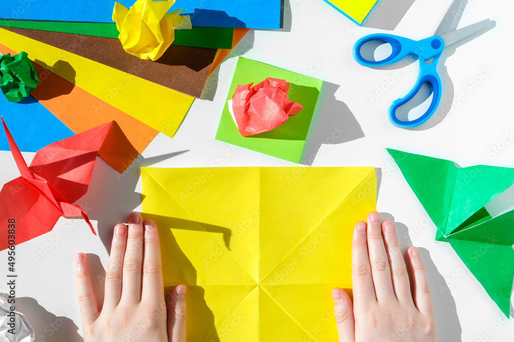 Paper crafts, scissors, colored paper sheets and scraps, on white table ...