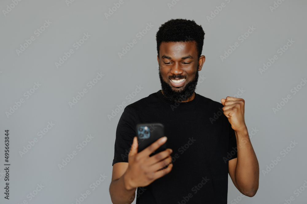 Excited african American man isolated on grey studio background hold ...