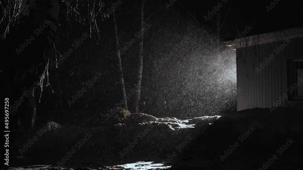 The blizzard is illuminated by a lantern. Large snow falls in the dark ...