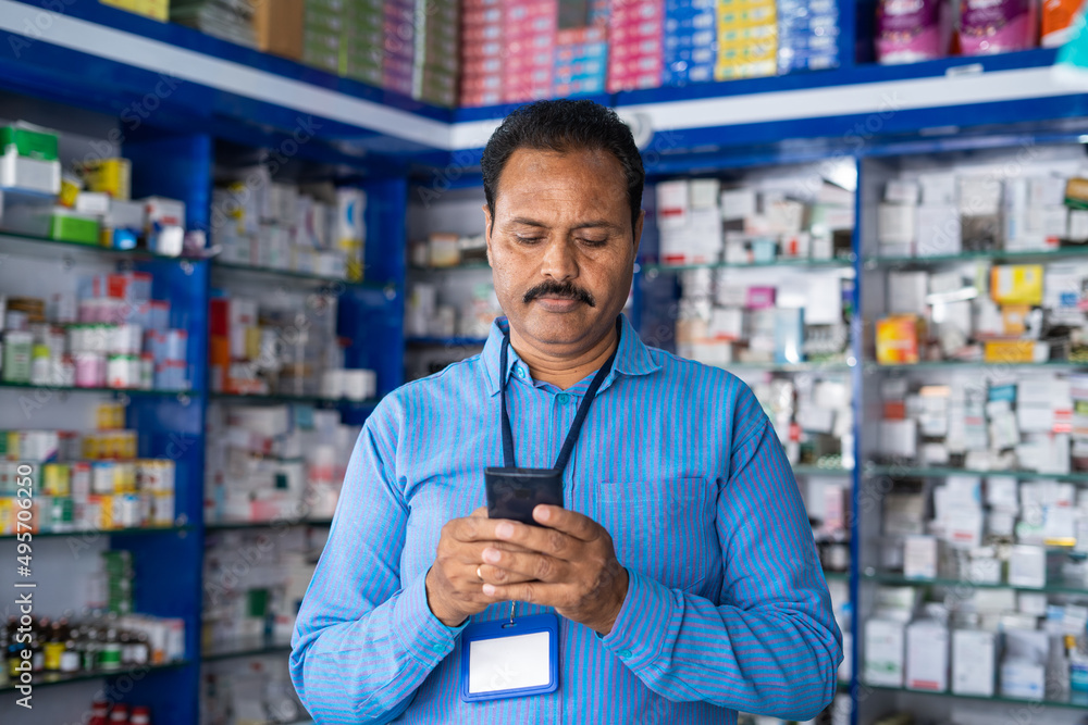 Pharmacist busy using mobile phone at retail pharma medical store ...