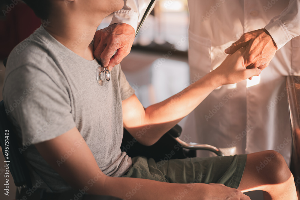 Hand of a kind doctor checking heartbeat to young man with disability ...