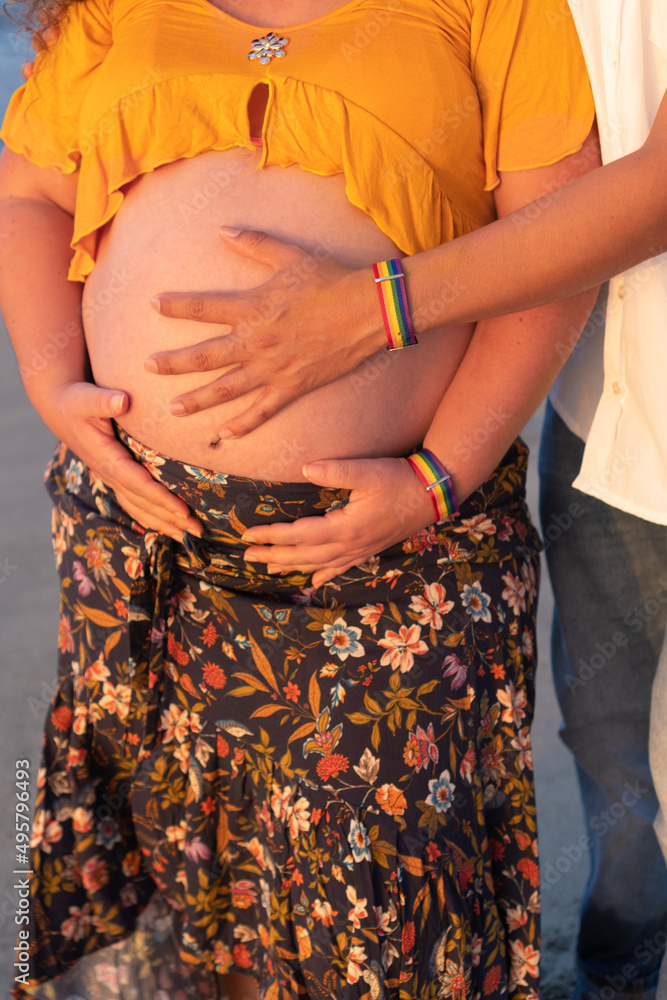 Unrecognizable Pregnant Lesbian Couple With Rainbow Handle Relaxing On