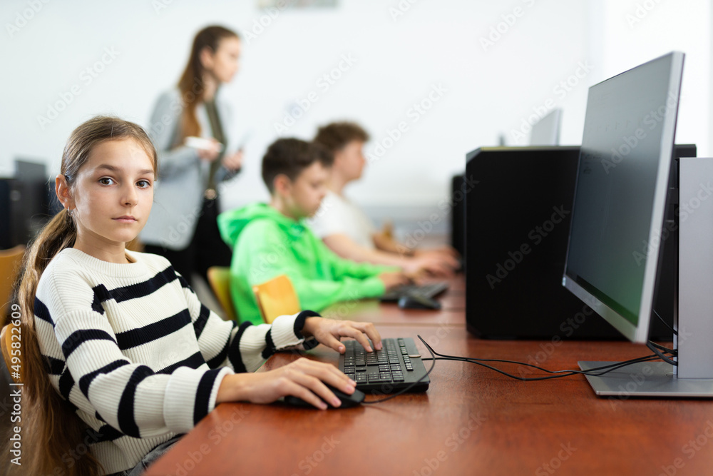 Portrait of interested tween girl during lesson in computer room of ...