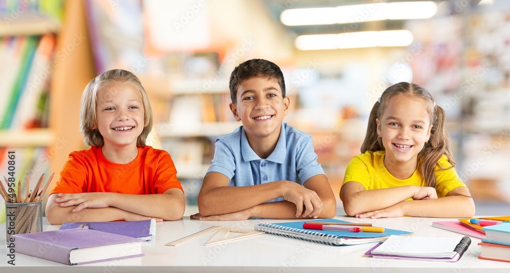 Child are sitting at a school desk, writing, his hand up. school ...