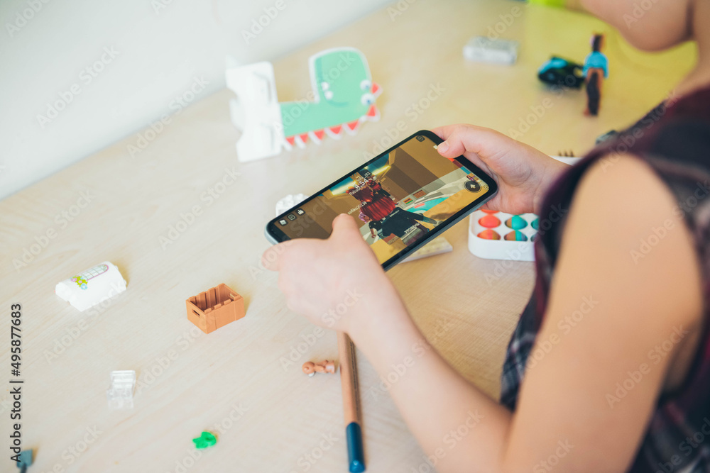 Little girl playing mobile games on her phone. Stock Photo | Adobe Stock