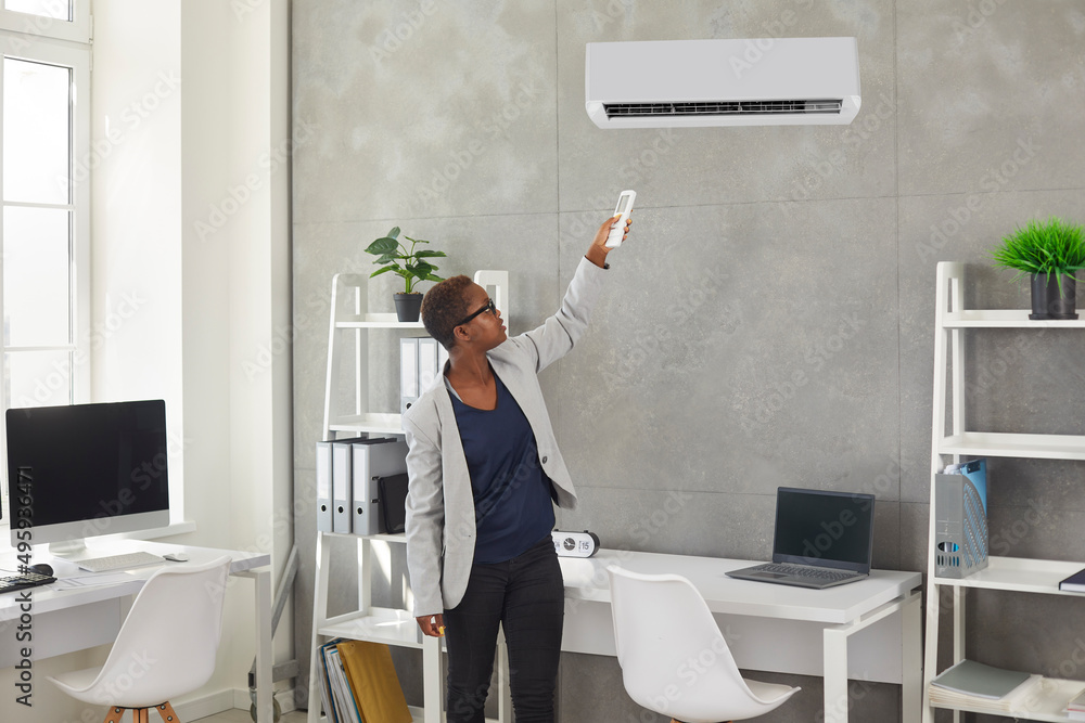 Woman turns on the AC at work. Black businesswoman standing in a modern ...