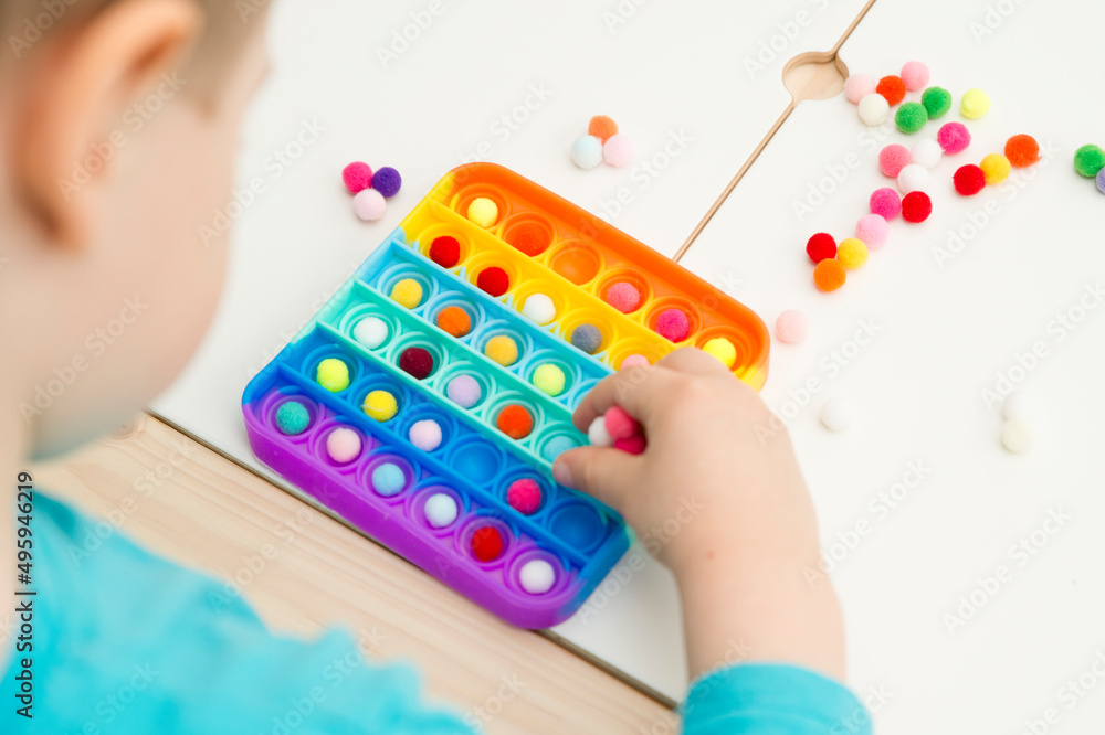 Child plays with sensory fidget toy Pop-it. Instrument for fine motoric ...