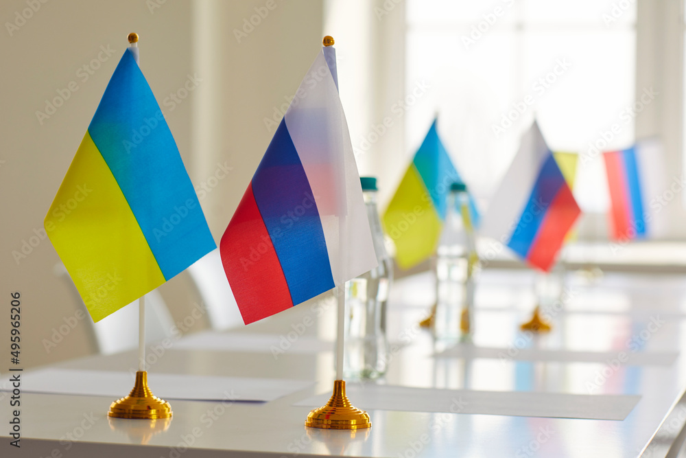 Negotiation table with water bottles and flags of Ukraine and Russia in ...