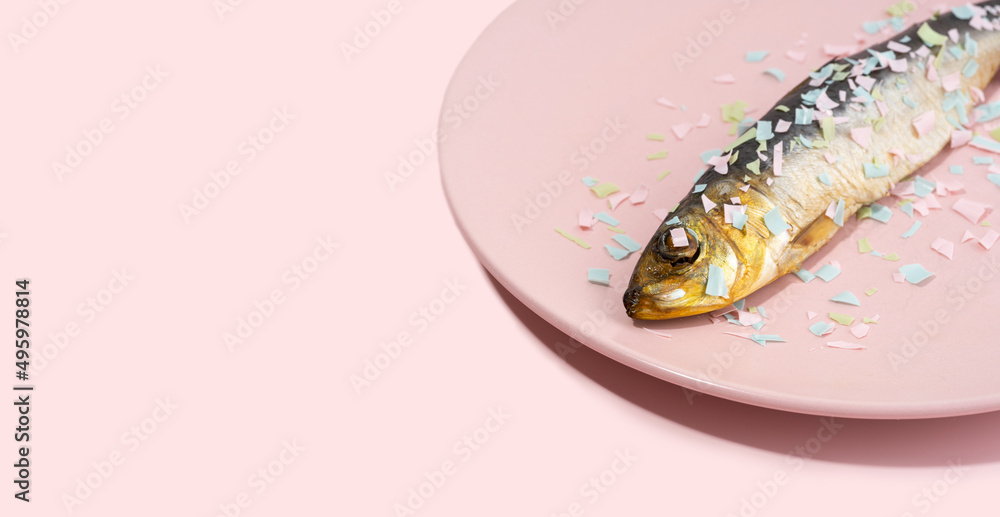Fish covered microplastic on a pink plate. Impact of micro plastic on ...