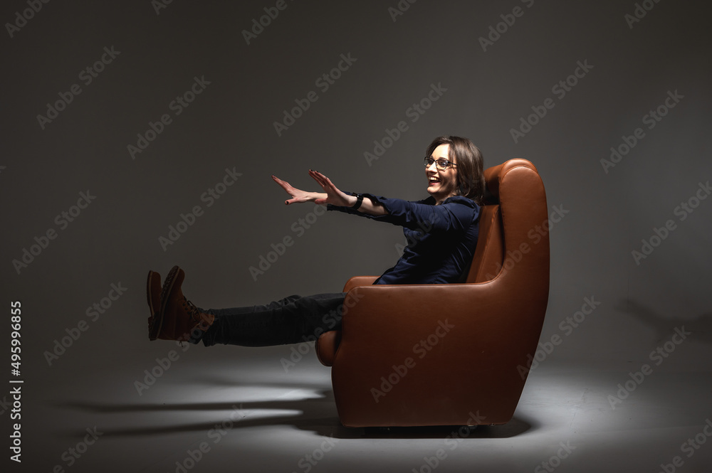 young beautiful emotional girl sitting on a soft brown leather chair ...
