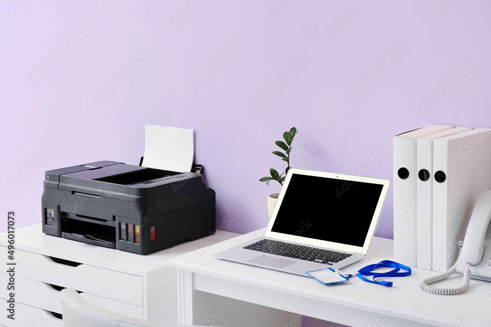 Workplace with modern laptop and chest of drawers with printer near ...