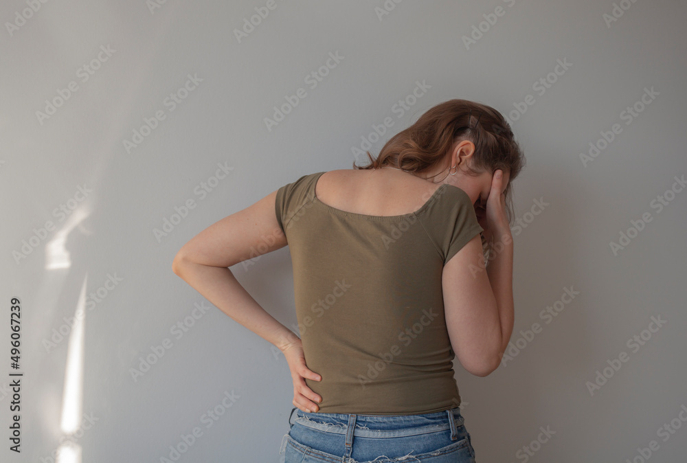 Sad woman with hand on her face, back view. Backache or kidney problem ...