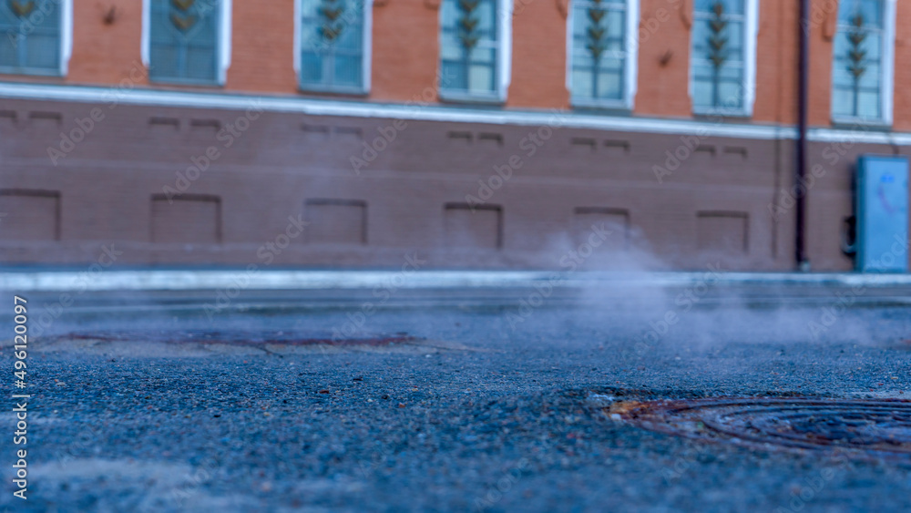 Fotka „Manhole cover in a paved street on a cold day, as steam escapes ...
