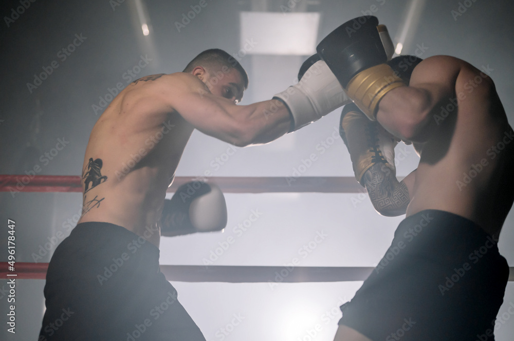 Two professional young muscular shirtless male boxers fighting in a ...
