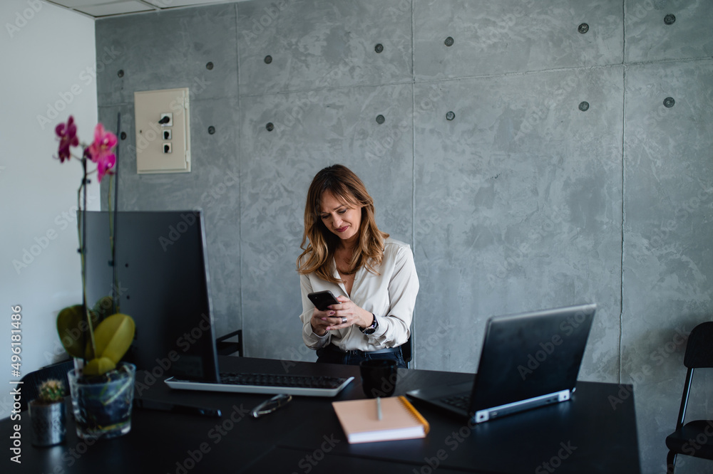 Handsome woman is typing messages on her smartphone while she's sitting ...