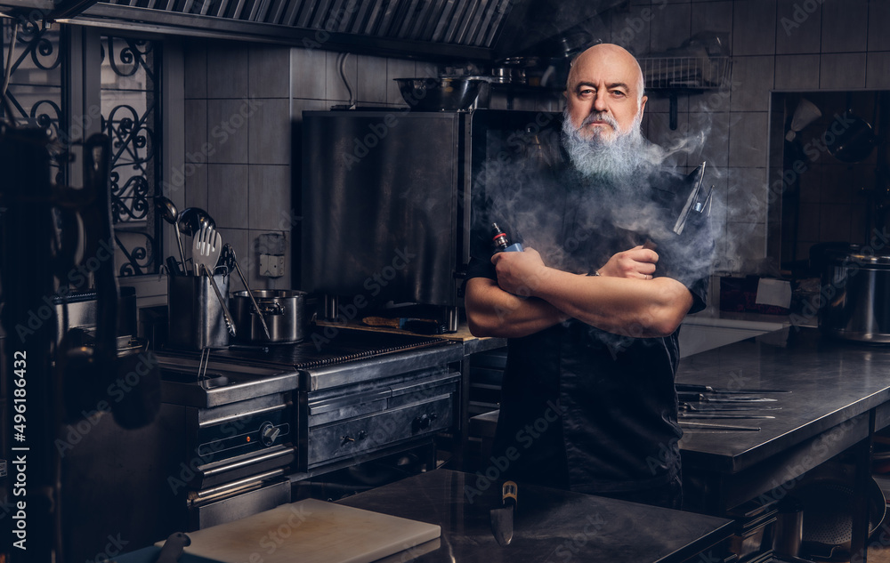 Bald old man chef smoking vape inside his kitchen Stock Photo | Adobe Stock