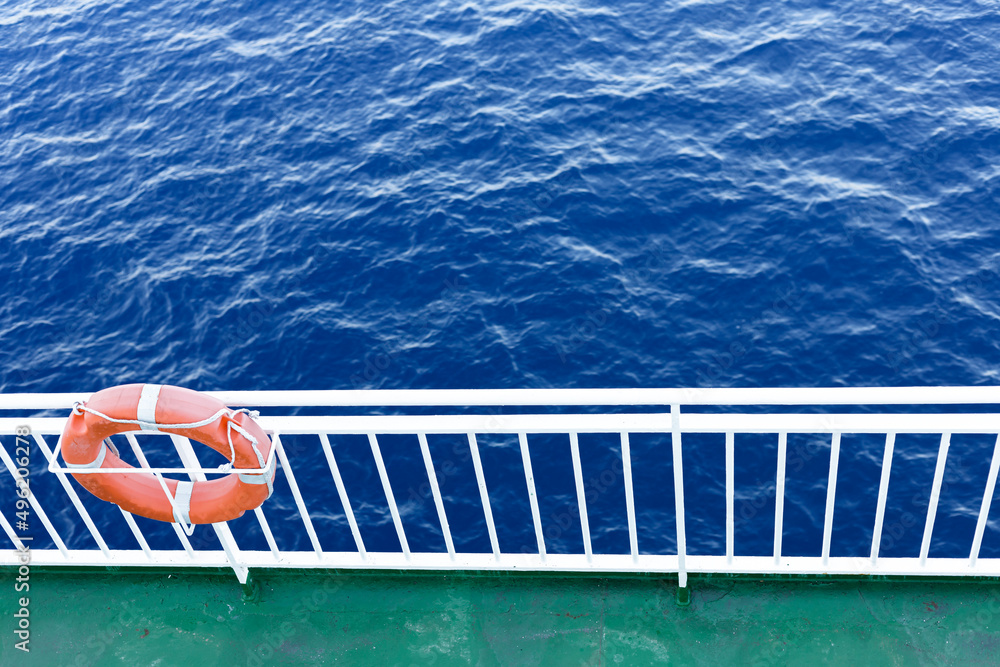 Lifesaver hanging in the guardrail of a ship with the blue water as ...
