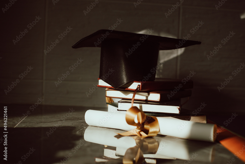 Foto de Birrete con libros apilados y diploma al lado. Concepto de ...