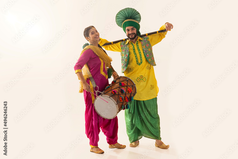 Sikh couple performing bhangra with drum and khunda during Baisakhi ...