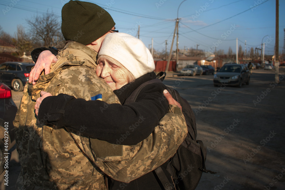 Naklejka Military son hugs an elderly mother goodbye. Mom hugs a ...