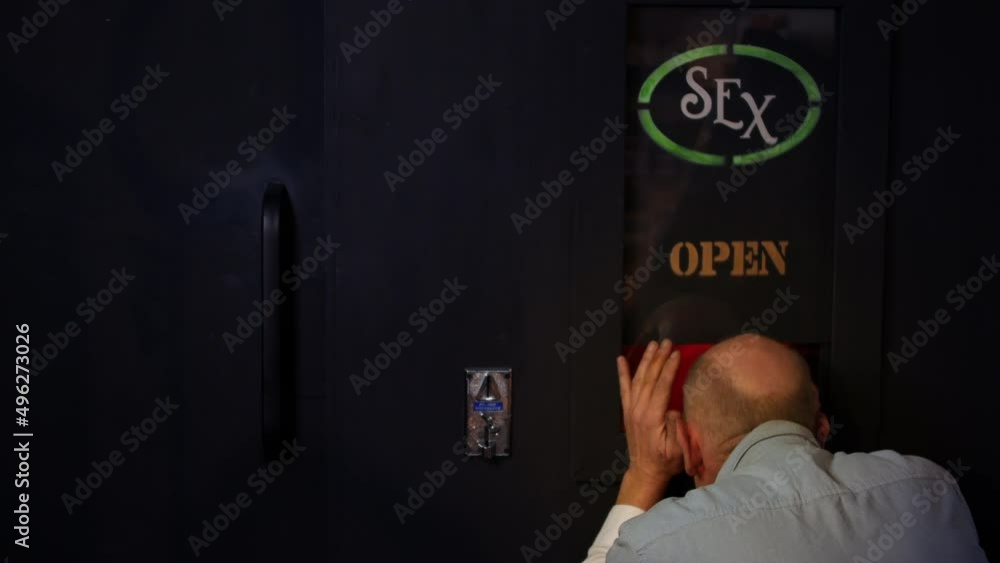Man at coin-operated peep show sex booth looking through a peephole at an erotic scene Stock ...