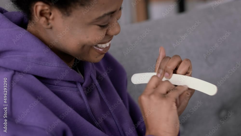 Black girl aligning her nails with nail file, making manicure at home ...