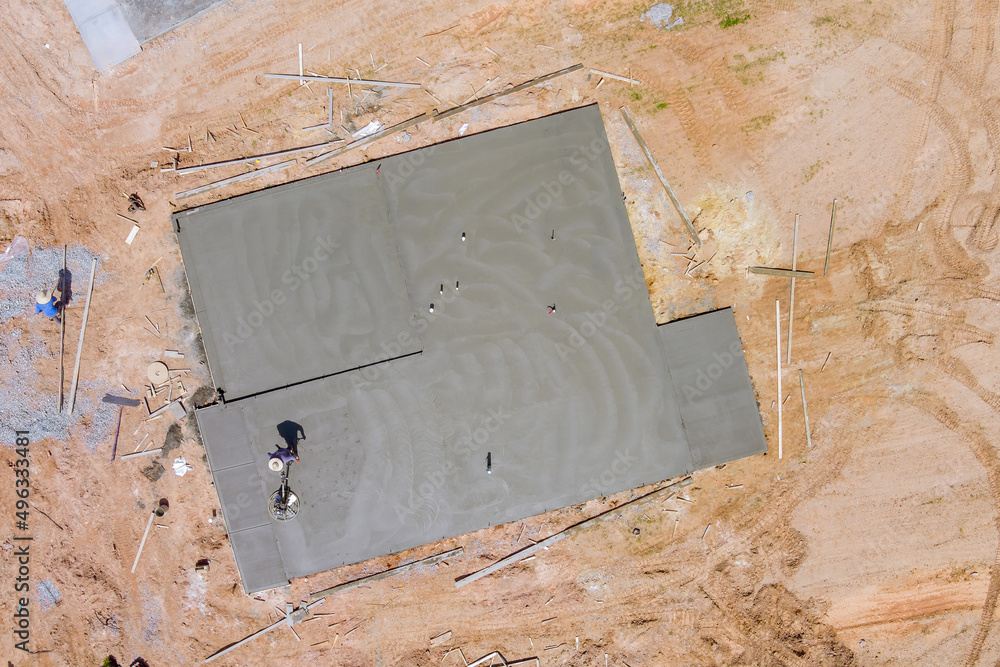 Construction worker grinding cement screed foundation on new house ...
