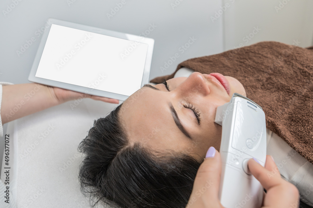 Woman receiving a facial analysis and diagnosis. Dermatologist holds a ...