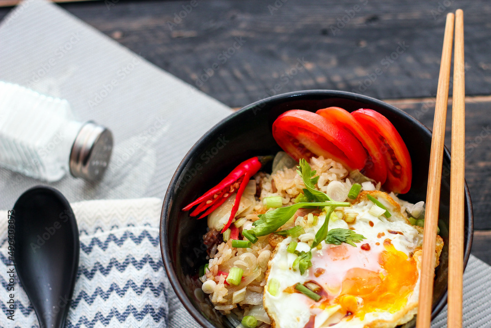 Japanese-style fried rice served in a black bowl with a fried egg and ...