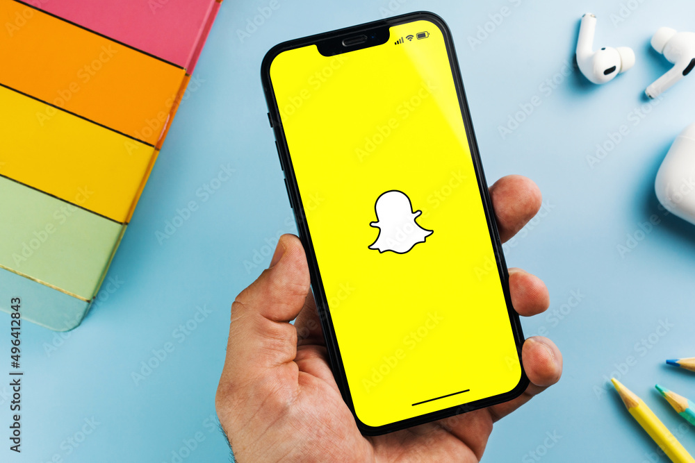 Man holding a smartphone with Snapchat app on the screen. Blue ...