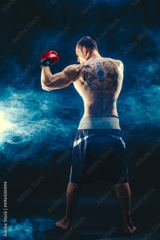 Back view of sportsman muscular boxer who fighting on black smoke ...