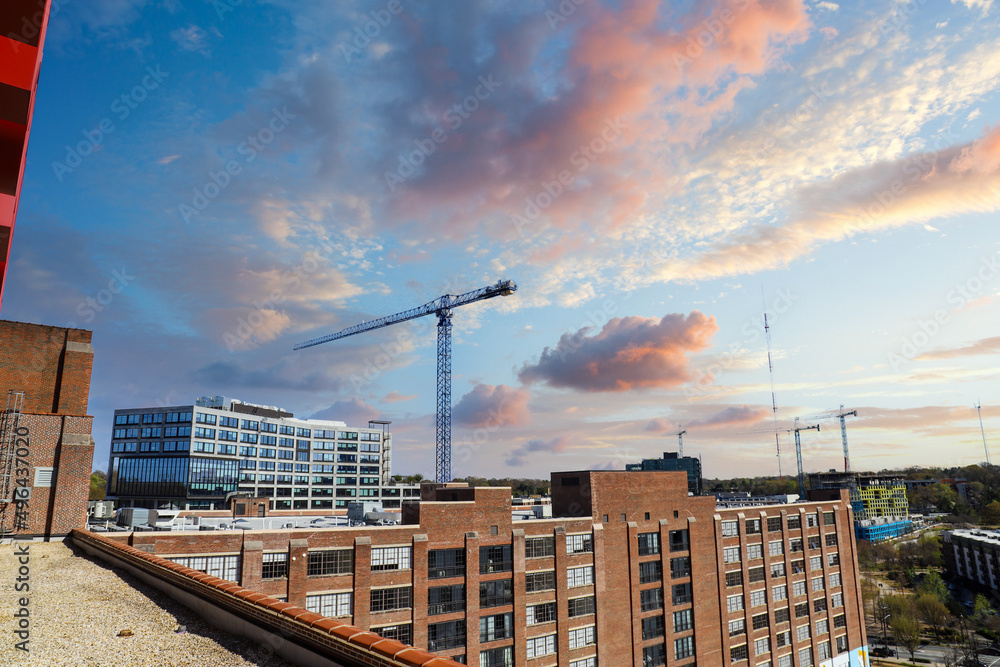 tall red brick buildings and glass skyscrapers with tall tower cranes ...