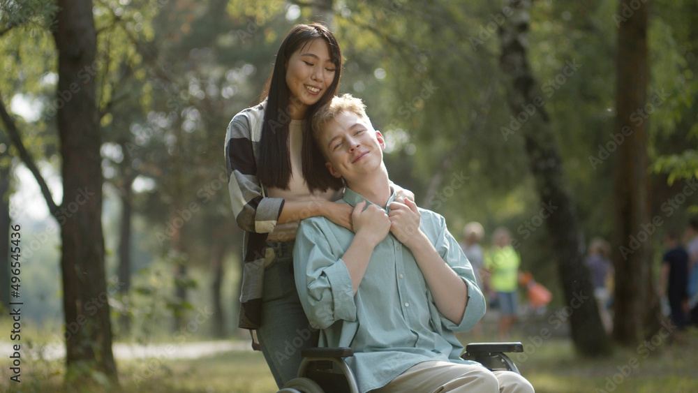 A pretty asian lady with long dark hair hugs her disabled young man in ...