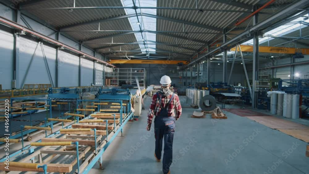 Shot back man engineer wearing safety uniform and hard hat walking ...