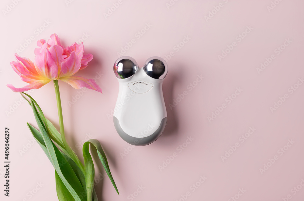 microcurrent facial toning device on pink background with beautiful ...