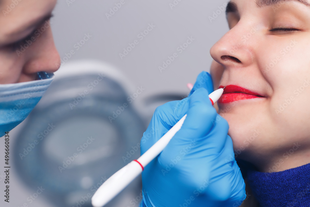 Permanent make up procedure. Lip makeup in tattoo salon. lip contour ...