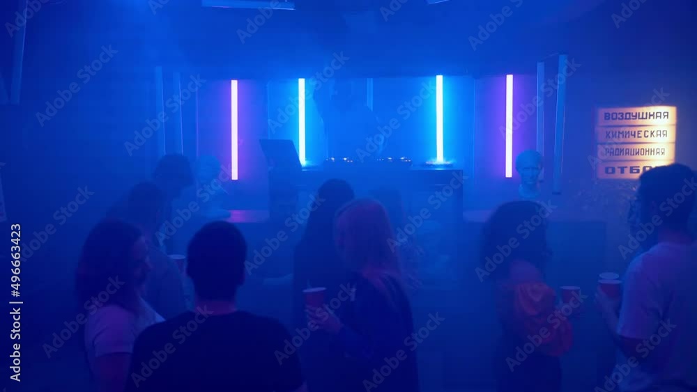 A crowd of people dancing on the dance floor of a nightclub under the ...