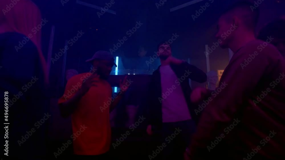 A crowd of people dancing on the dance floor of a nightclub under the ...