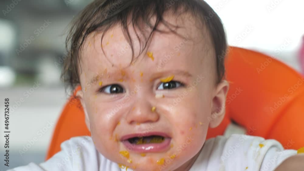 Close-up of a crying baby at a table for feeding children, crying and ...