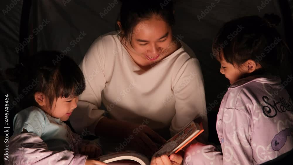 Mother reads a book of fairy tales for her children while sitting in a ...