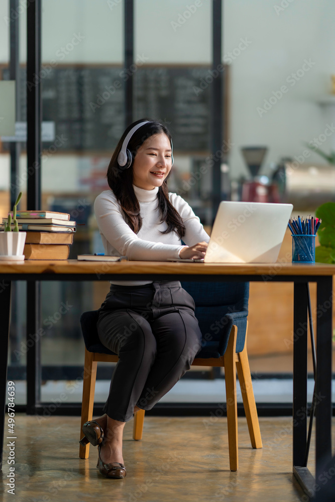 study abroad Asian girl wearing headphones watching laptop while doing ...