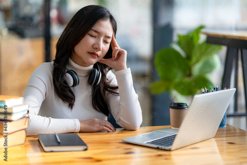 study abroad Asian girl is stressed and has a headache While doing ...
