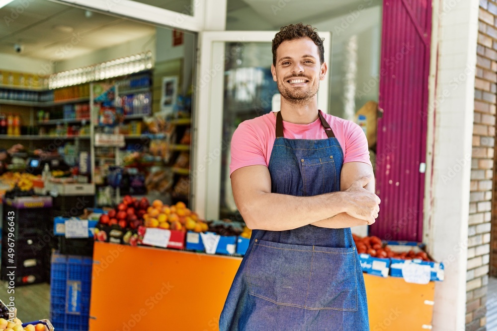 Foto de Young hispanic worker wearing apron standing with arms crossed ...