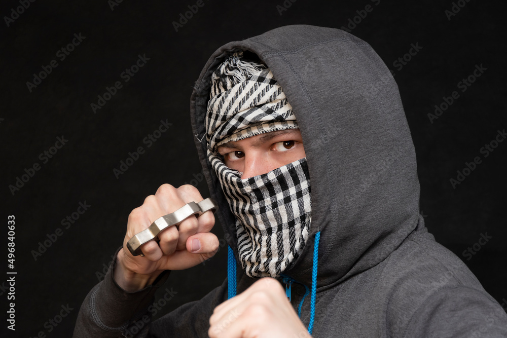 Metal brass knuckles in the hands of a man hiding his face,prohibited ...