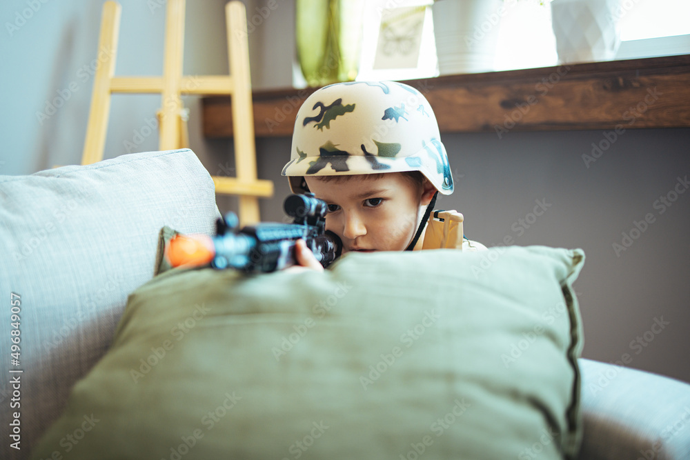 Little boy playing soldiers in living room. In his imagination the boy ...