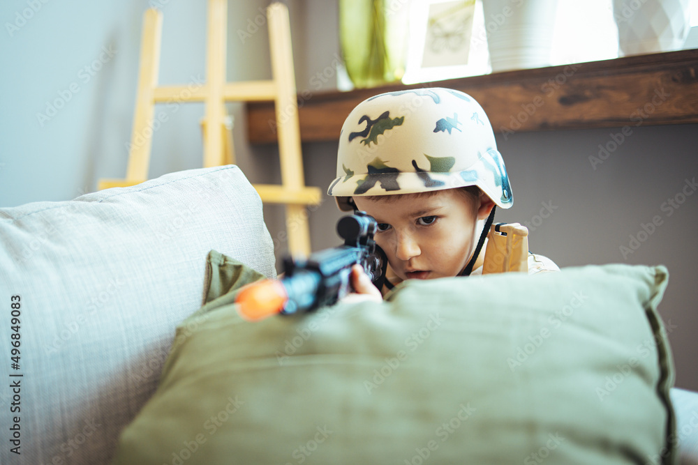 Foto de Little boy playing soldiers in living room. In his imagination ...