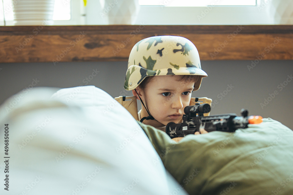Little boy playing soldiers in living room. In his imagination the boy ...